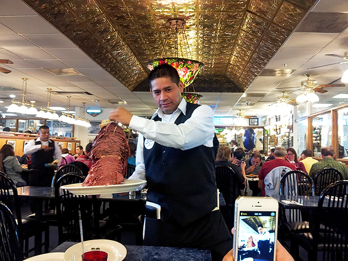 The server presents what appears to be the entire meat section of a supermarket, artfully arranged between two slices of bread. Performance art you can eat!