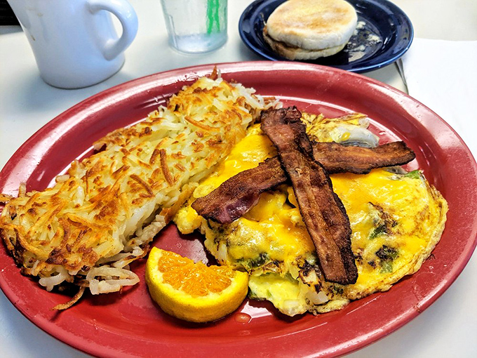 The breakfast trinity: crispy hashbrowns, a perfectly executed omelet, and bacon arranged like an edible work of modern art.