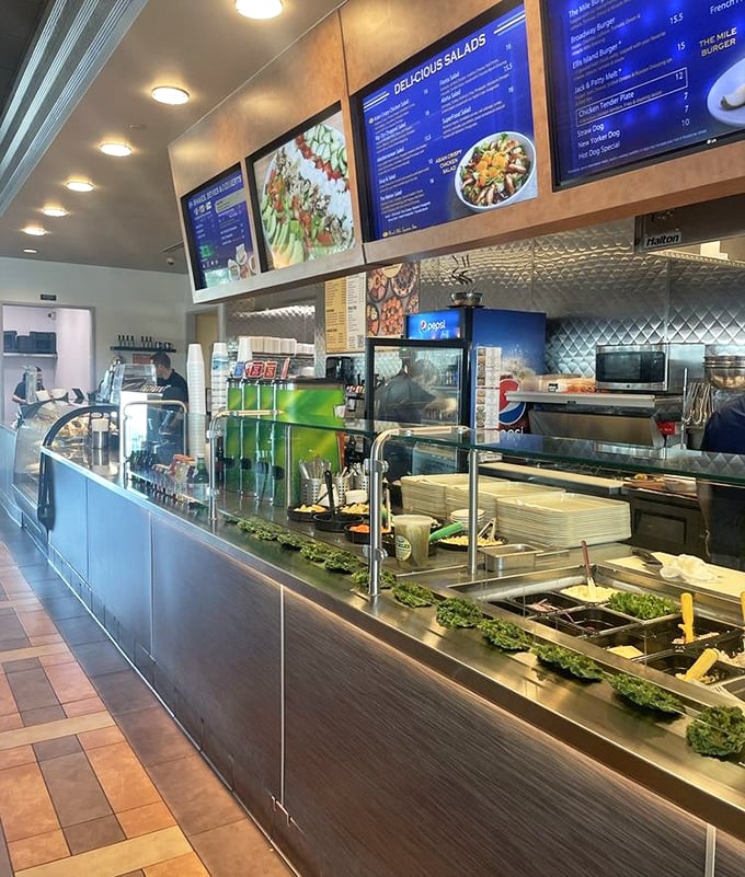 Behind the scenes magic! The cafeteria-style counter reveals the artistry behind each sandwich, where deli masters transform ingredients into edible masterpieces.