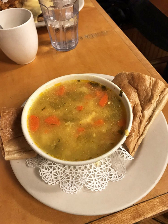 A bowl of golden chicken soup that whispers "comfort" in a language that requires no translation, served with respect on a proper doily.