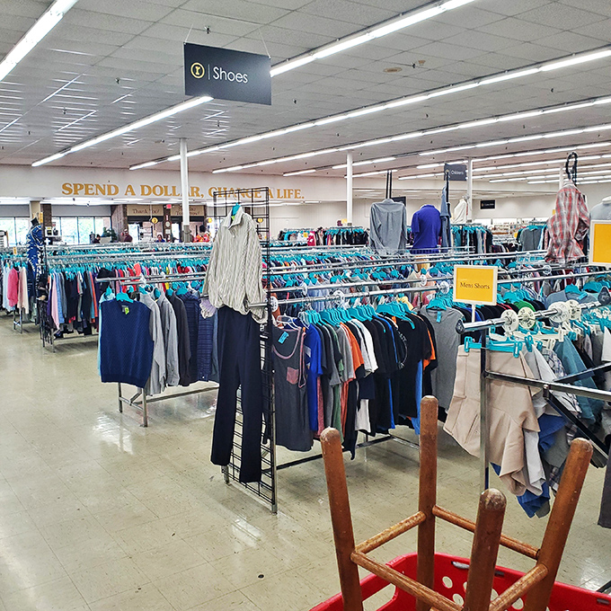 The clothing section stretches toward retail infinity. That "Spend a Dollar, Change a Life" sign reminds you this shopping spree has purpose.