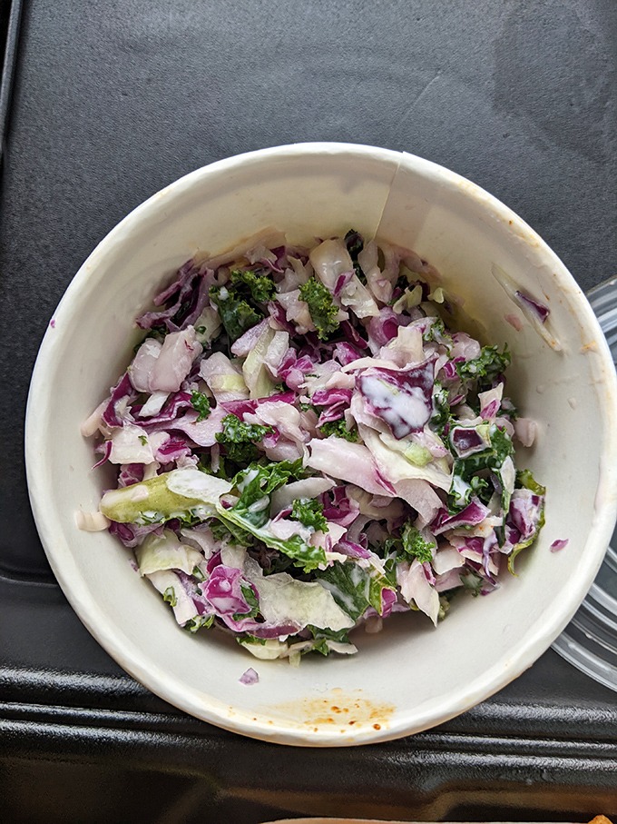 The kale slaw brings a refreshing crunch and color to the party, proving vegetables can hang with the cool kids when properly dressed.