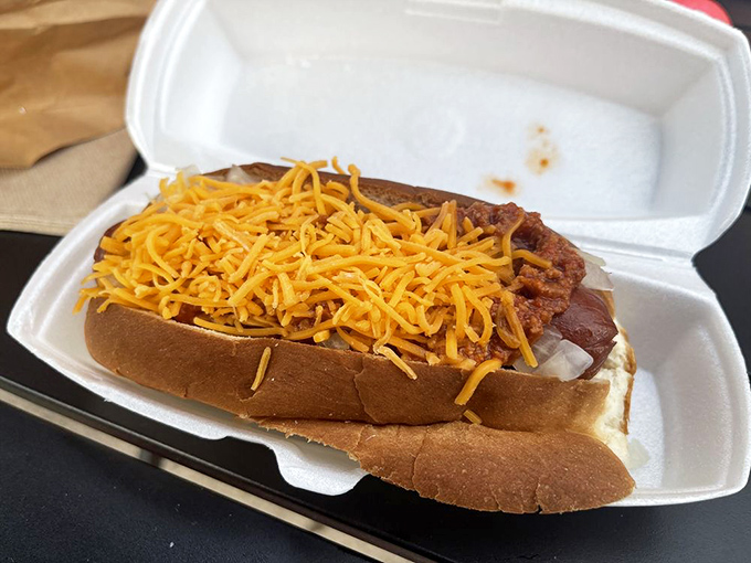 A coney dog in its natural habitat: nestled in paper, topped with a blanket of chili and cheese, waiting for its destiny.