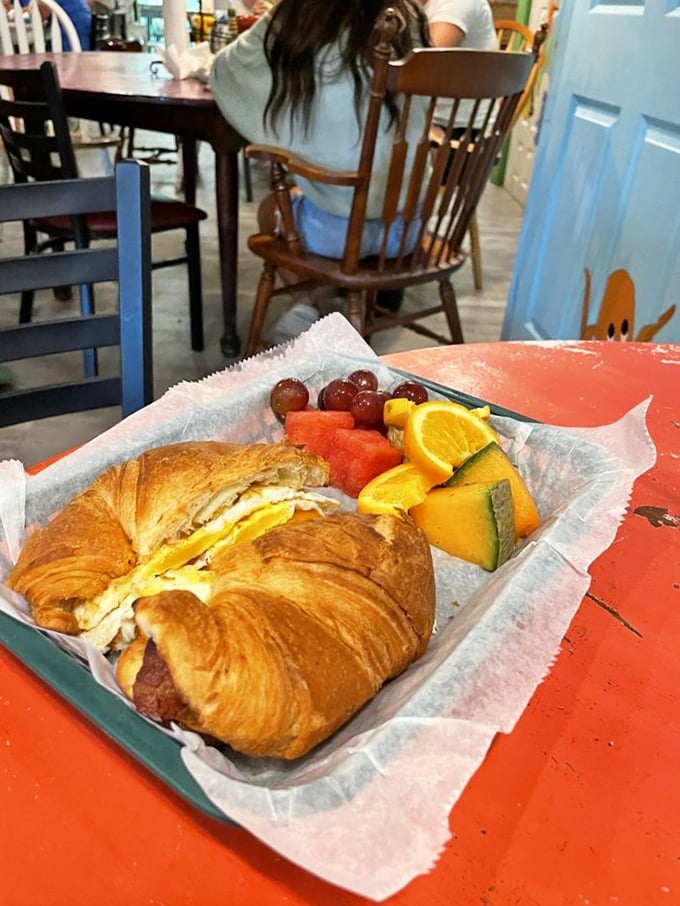 Buttery croissant meets breakfast essentials, served with fresh fruit that momentarily convinces you this is a balanced meal. 