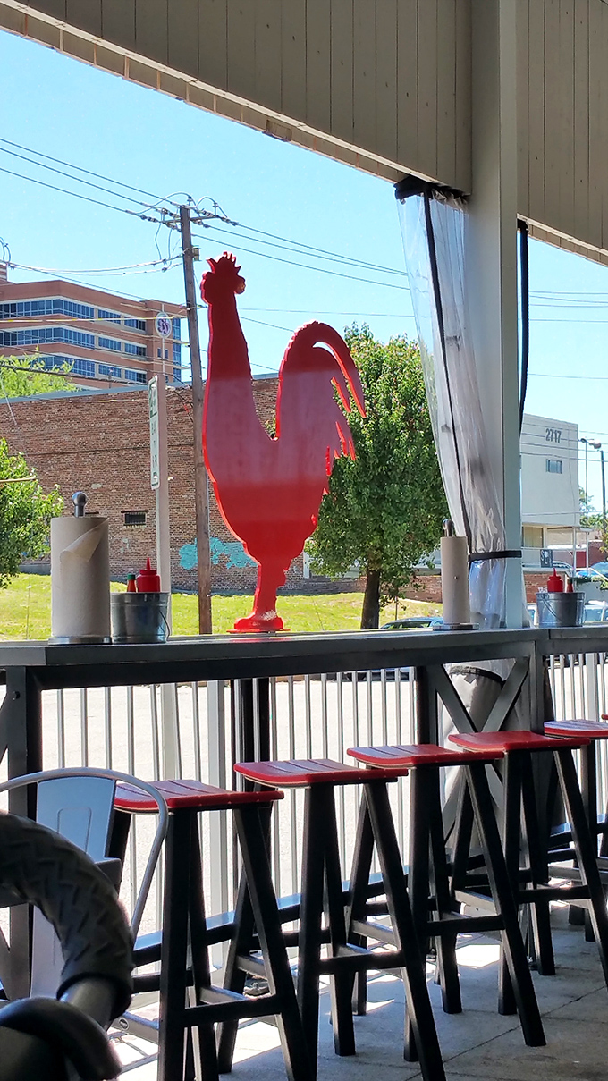 The red rooster watches over outdoor diners like a fiery guardian angel of Nashville hot chicken tradition.