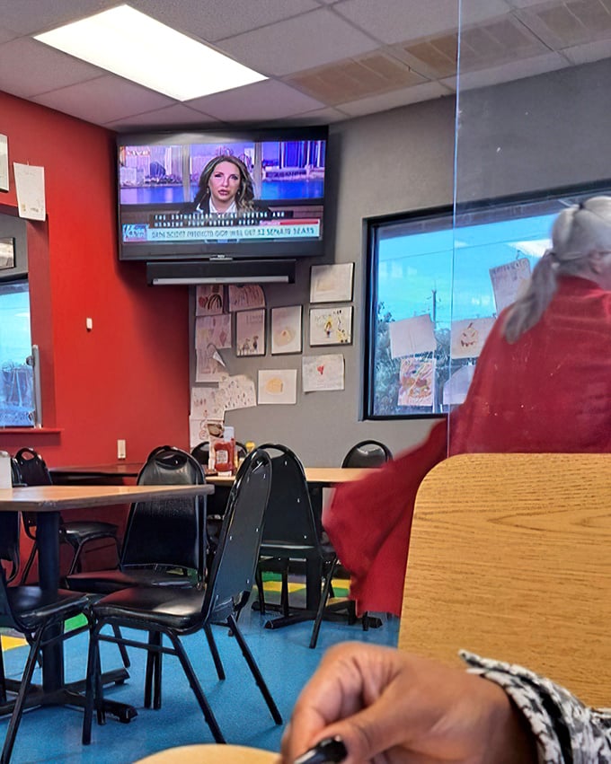 Even the TV in the corner knows not to compete with the main attraction here. The red walls have absorbed decades of satisfied sighs.