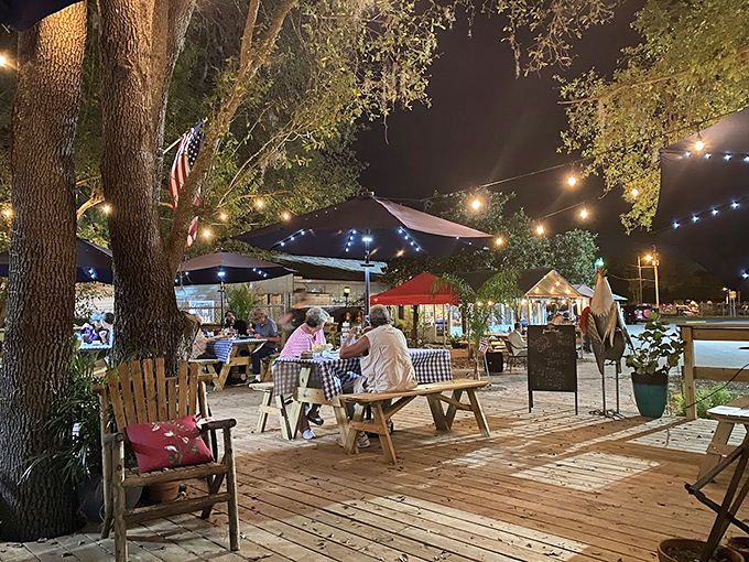 As night falls, string lights transform the porch into a magical dining room under the stars. Oak trees stand guard over checkered tablecloths and happy conversations.