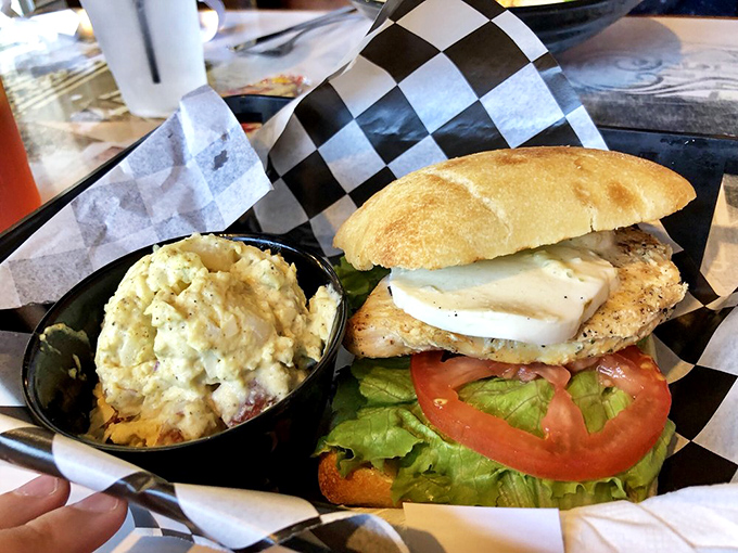 A chicken sandwich that understands balance&mdash;creamy potato salad on the side, fresh vegetables within, all served on checkered paper like a picnic.