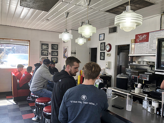 Morning light streams through windows onto checkered floors where strangers become friends over coffee and shared appreciation for simple perfection.