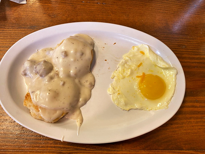 Country gravy cascading over a fresh-baked biscuit like a warm Southern blanket, with an egg sunny enough to brighten any morning.