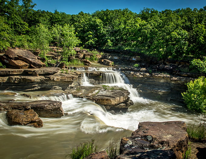 Bluestem Falls cascades over ancient rock formations, creating a natural oasis that feels worlds away from everyday concerns.