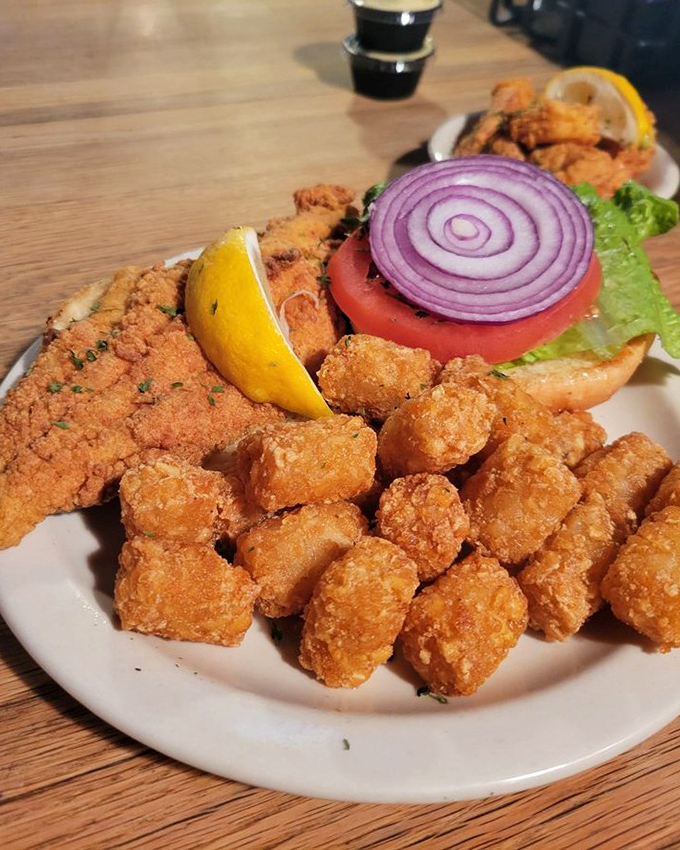 A sandwich that requires both hands and a Southern appetite. That purple onion ring is the crown jewel of this fried seafood masterpiece.
