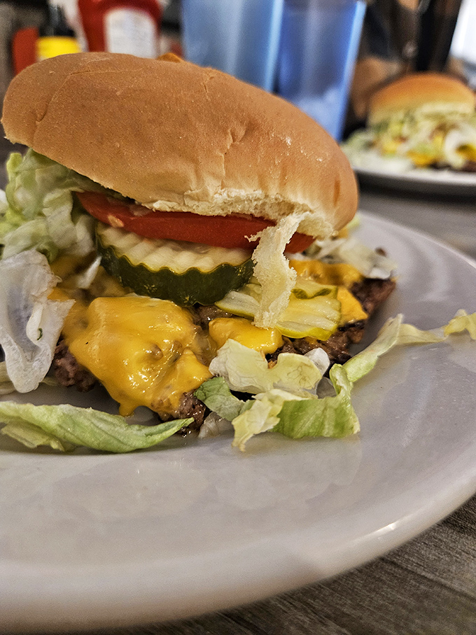 Behold the cheeseburger in its natural habitat—melty American cheese cascading down a hand-formed patty like a yellow waterfall of joy.