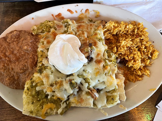 A plate that whispers "comfort" but shouts "flavor" &ndash; where melted cheese blankets perfectly stuffed enchiladas alongside festive Mexican rice.