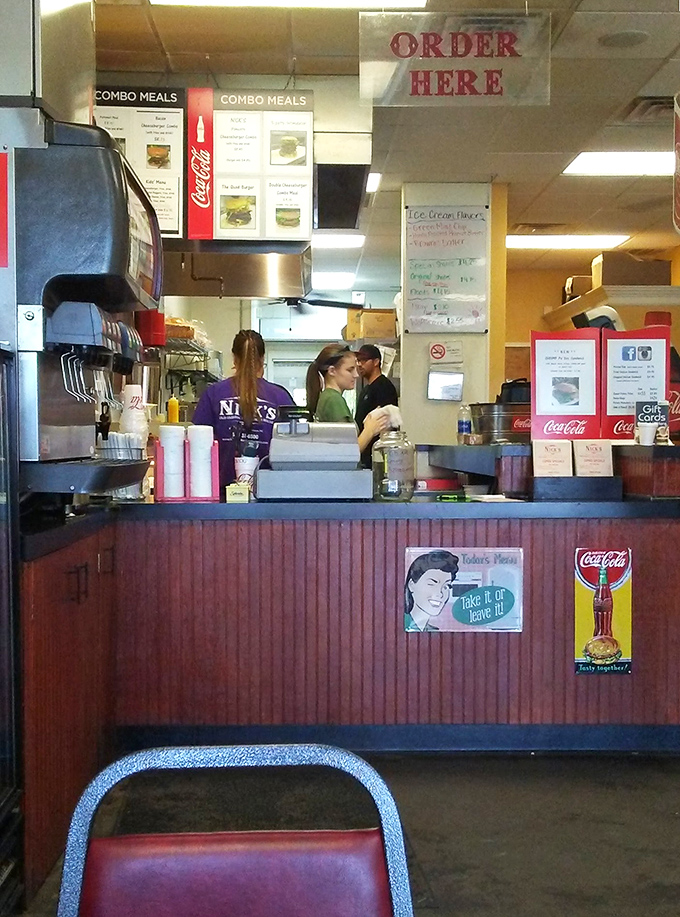 The ordering counter&mdash;where dreams become reality. Those vintage Coca-Cola signs aren't decoration; they're time machines to simpler days.
