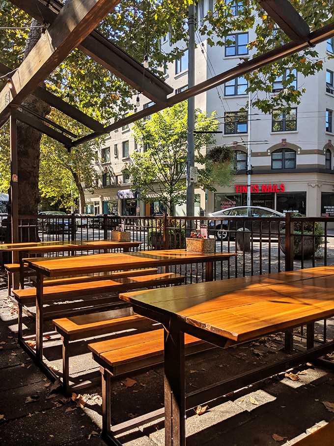 Outdoor seating bathed in dappled sunlight offers a front-row view of Seattle life passing by, with wooden tables that have stories to tell.