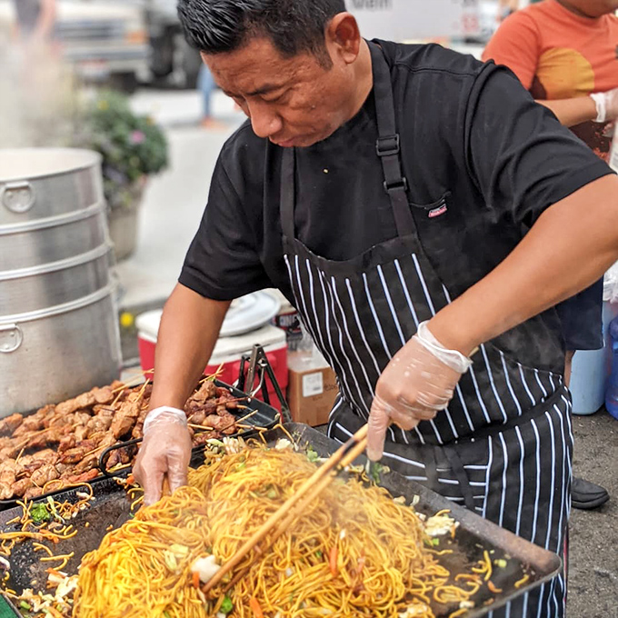 This chef conducts a symphony of noodles and protein, his chopsticks the baton that orchestrates a street food masterpiece.