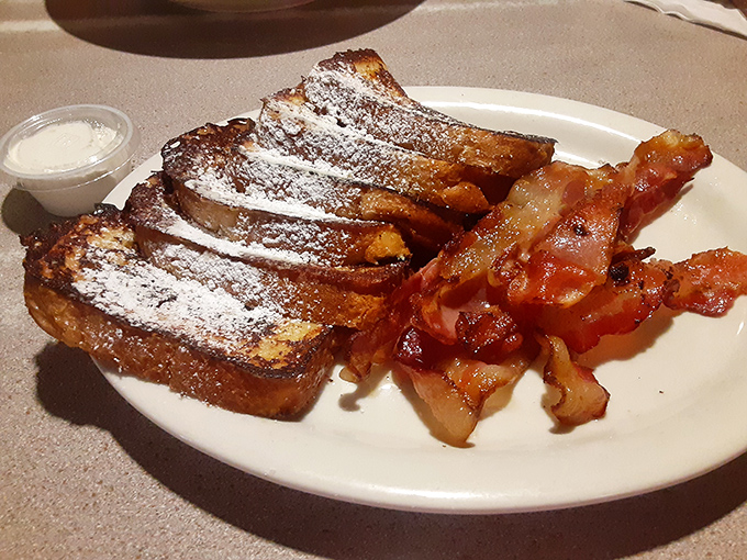 French toast that's lived its best life &ndash; dusted with powdered sugar, paired with bacon, and ready for its close-up.