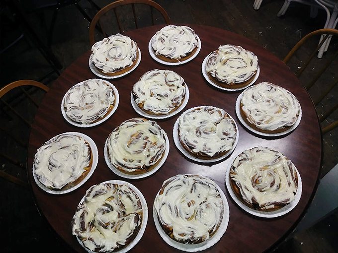 Fresh-baked cinnamon rolls await their frosting baptism, arranged in circular perfection like a sweet clock counting down to indulgence.