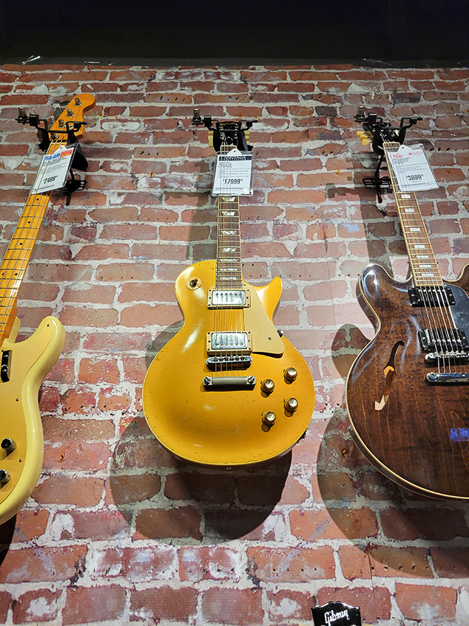 Vintage guitars hang like rock and roll ghosts against exposed brick, each one holding the echoes of power chords past.