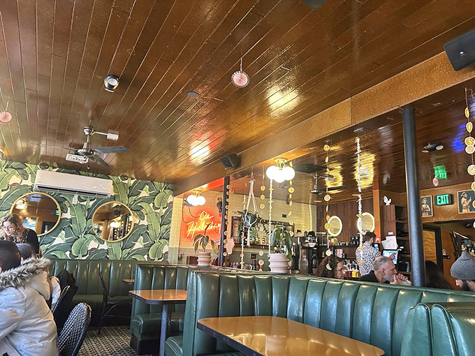 Green booths against tropical wallpaper create the perfect backdrop for your dining adventures. Those round mirrors reflect all the good times.