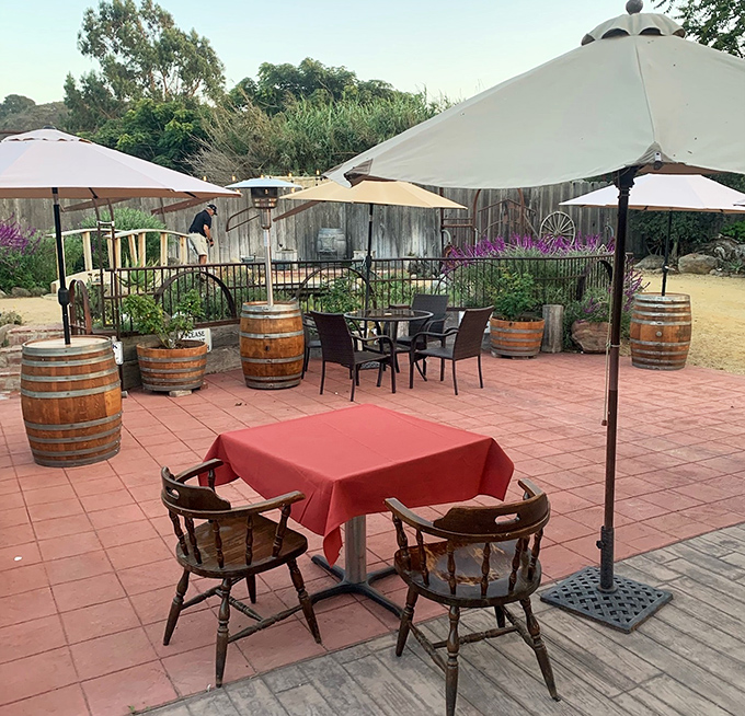 The outdoor patio whispers of California evenings where wine barrels and umbrellas create the perfect backdrop for memories in the making.