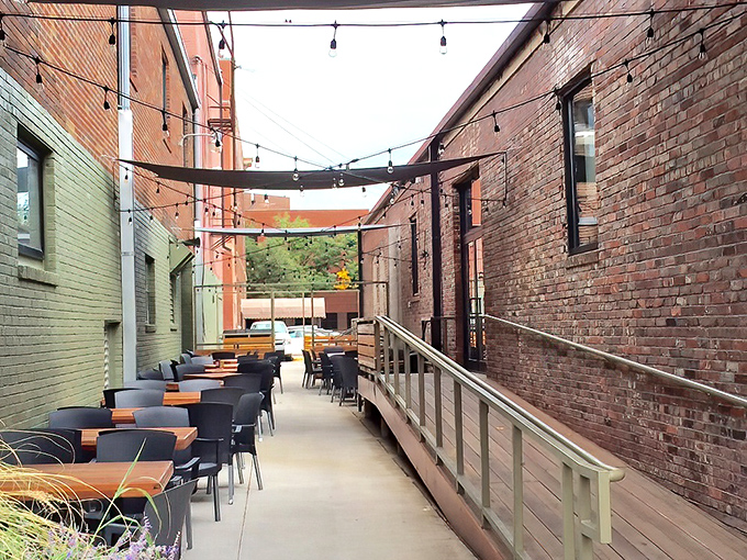 The outdoor alleyway seating transforms urban brick into an intimate dining experience, string lights adding just the right touch of magic.