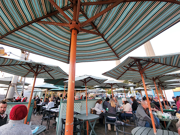 Striped umbrellas sheltering happy diners&mdash;a colorful mosaic of conversations, clinking glasses, and the collective joy of eating outdoors by the sea.