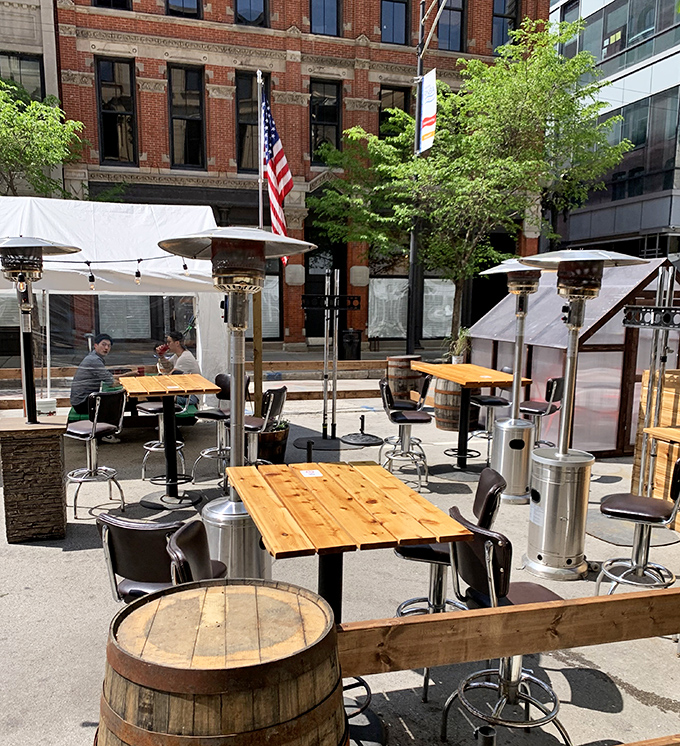 Outdoor dining with barrel tables and a city backdrop. Urban barbecue paradise where fresh air enhances the smoky perfume of nearby plates.