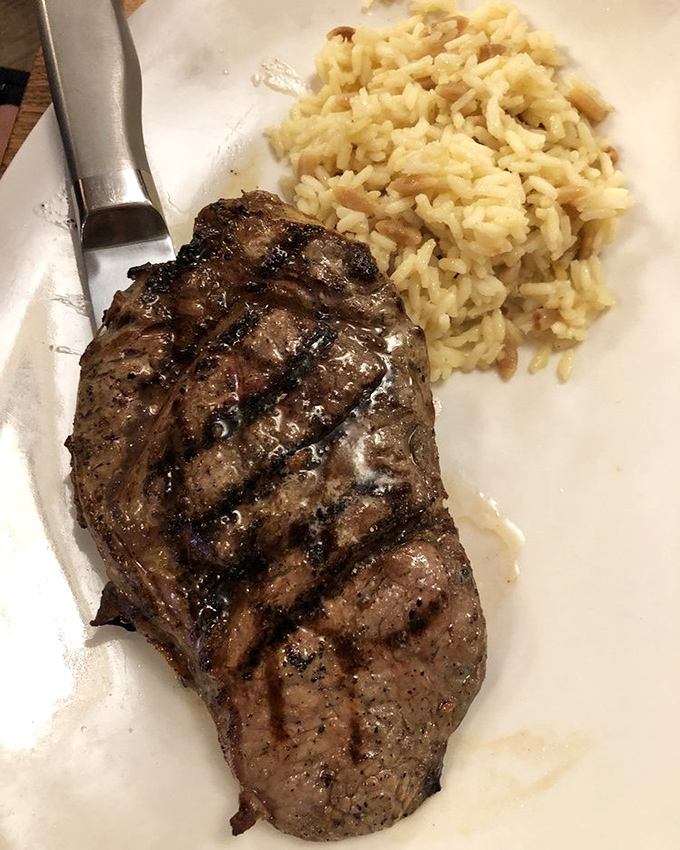 A ribeye with perfect grill marks lounging next to rice pilaf&mdash;it's the culinary equivalent of a power couple relaxing after conquering the world.
