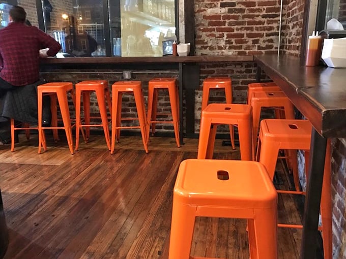 Orange stools pop against weathered wood and brick, creating a space that's both industrial-cool and warmly inviting. Function meets Philadelphia charm. 