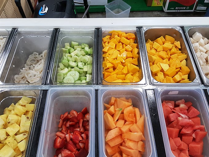 Fresh fruit paradise! These colorful trays of watermelon, mango, and cucumber wait to be transformed into refreshing snacks for hungry shoppers.