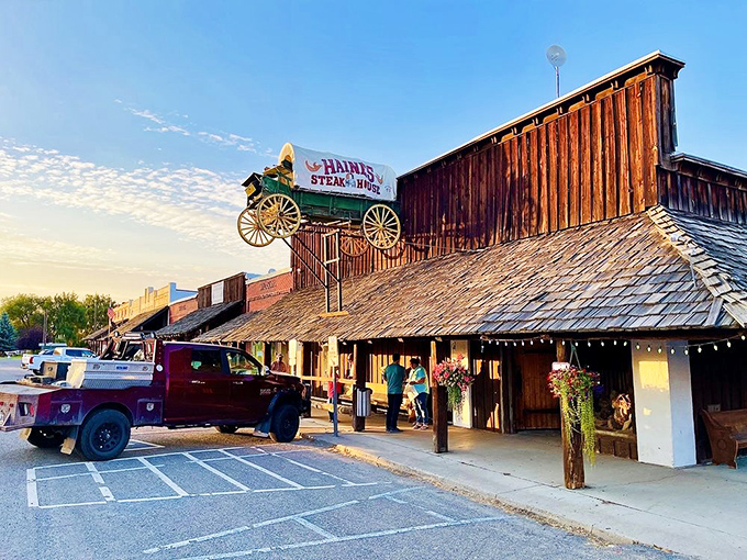 Golden hour at the steak house. As the sun sets behind the rustic wooden exterior, hungry diners arrive for their appointment with beef destiny.