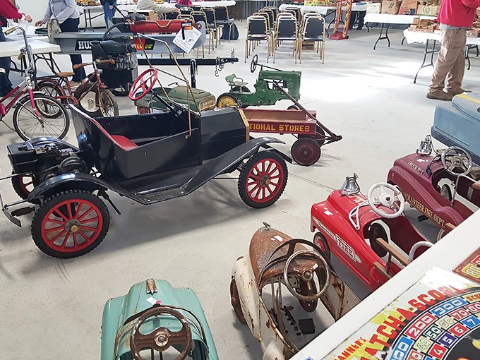 Pedal cars from America's automotive golden age sit in silent formation, their chipped paint and worn wheels telling stories of childhood adventures long past.