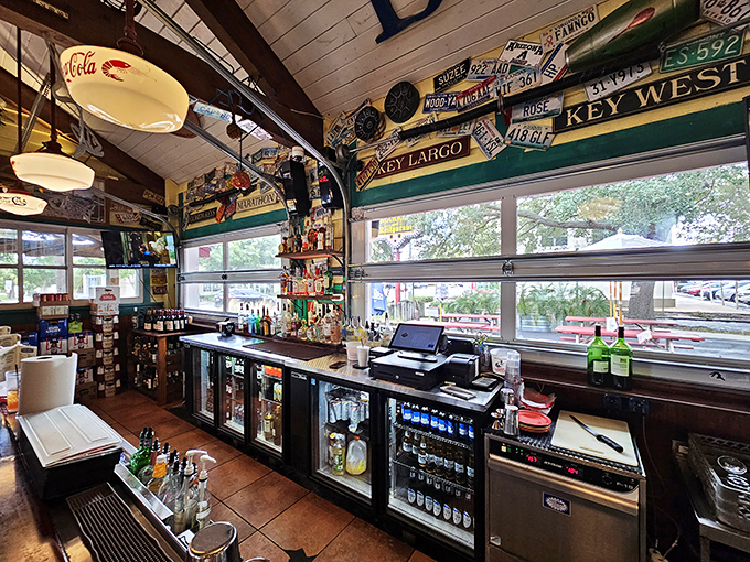 The bar area, where license plates and coastal memorabilia tell stories of road trips past, while cold drinks promise adventures to come.
