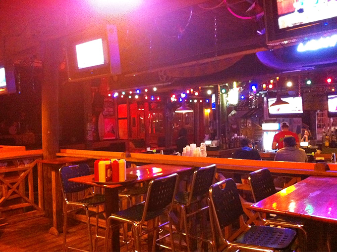 The bar glows like a sunset-hued aquarium where drinks flow and stories grow taller with each round ordered.