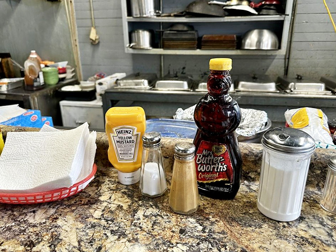 The heart of operations: where breakfast dreams materialize from skilled hands working magic behind a simple red-checkered counter.