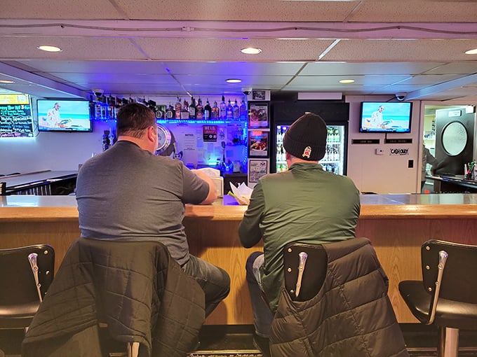 Two patrons at the bar demonstrate proper Wisconsin form: jackets on chairs, eyes on game, chicken within reach.