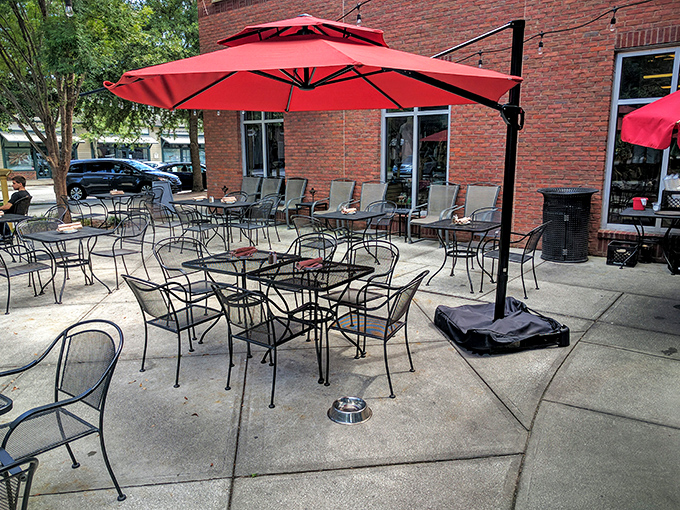 The outdoor patio—where fresh air meets comfort food. Those red umbrellas provide shade for both your table and your food envy.