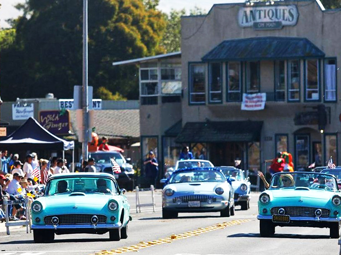 Classic cars parade down Main Street, celebrating automotive history with chrome that gleams like childhood summer memories.