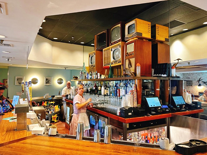 The bar doesn't just serve drinks—it broadcasts nostalgia from vintage TVs stacked like a mid-century electronics store display.