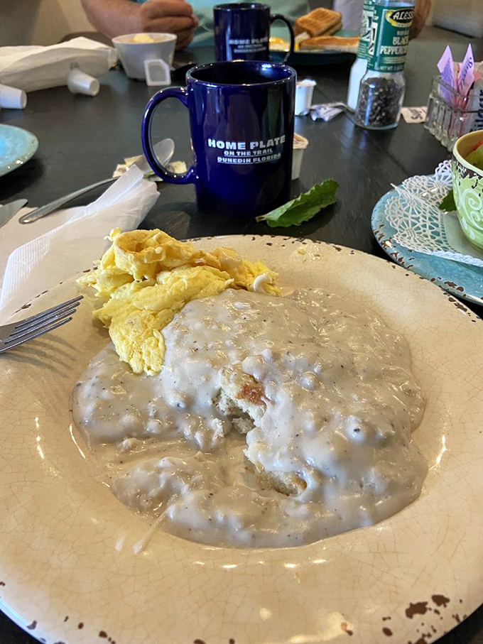 Biscuits swimming in sausage gravy with eggs standing by for moral support. The blue mug promises coffee strong enough to match this breakfast's ambition.