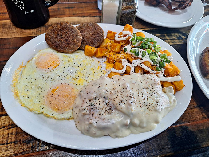 Two sunny-side up eggs flanking sausage patties with a side of sweet potato hash&mdash;a breakfast plate that demands to be photographed.