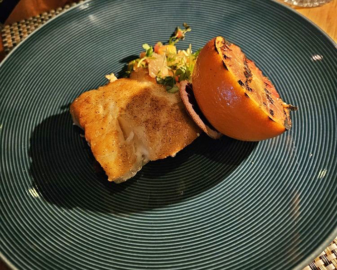 A perfectly cooked piece of fish alongside a charred citrus half&mdash;simple, elegant, and proof that sometimes less truly is more.
