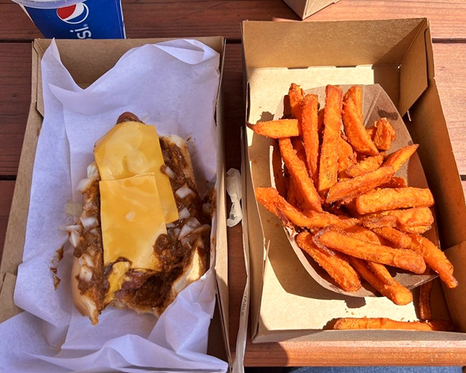A study in contrasts: the humble cardboard container elevates rather than diminishes these golden sweet potato fries and chili-cheese masterpiece.