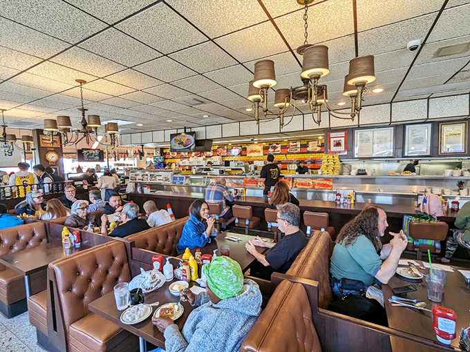 A bustling dining room where strangers become temporary neighbors united by the universal language of "mmmmm." The deli counter buzzes with activity in the background.