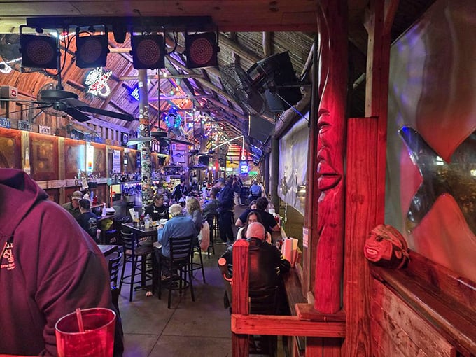 As evening falls, the tiki bar transforms into a neon-lit gathering spot where strangers become friends over grouper sandwiches and cold beer.
