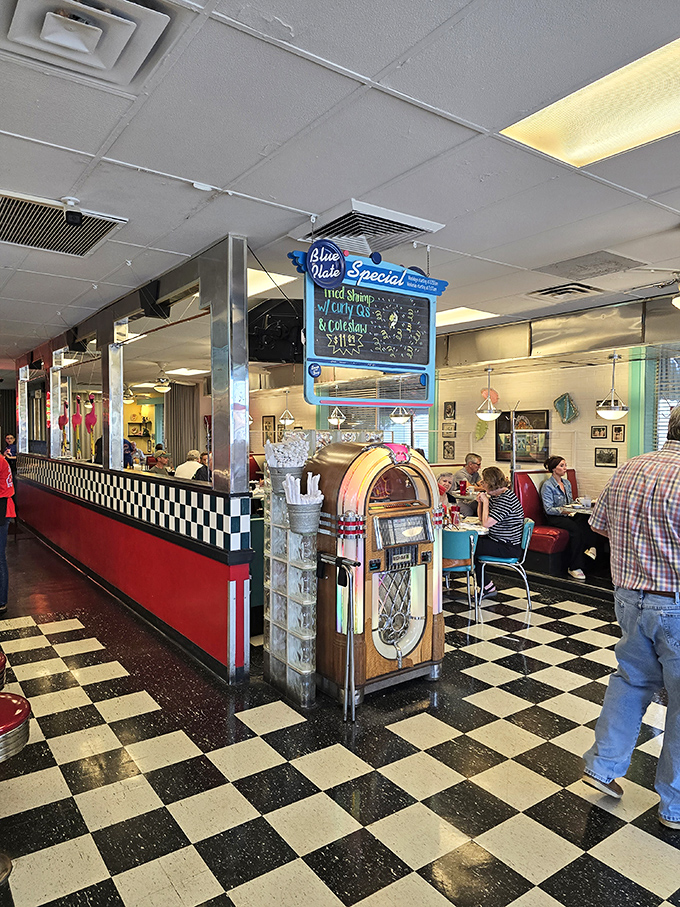 The vintage jukebox stands sentinel in a sea of checkerboard tiles, promising musical accompaniment to your gastronomic adventure.