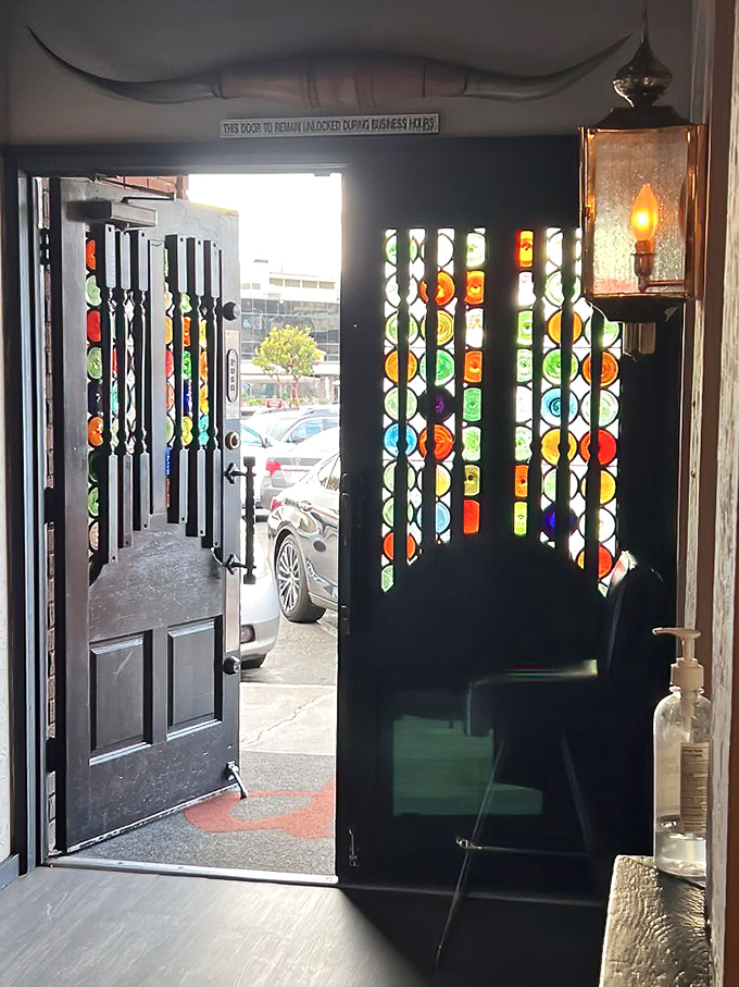 The stained glass entrance beckons like a portal to a simpler time when dinner was an event and smartphones stayed in pockets.