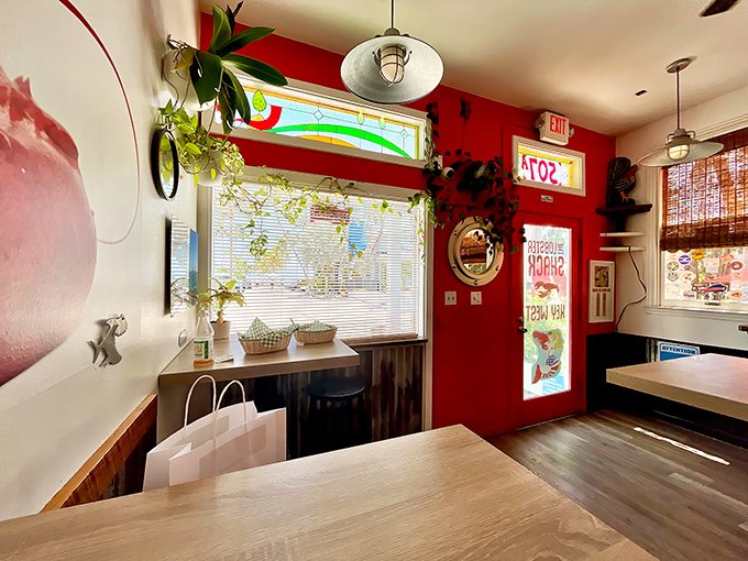 Plants that frame perfection. The interior's vibrant red walls and stained glass window create a shrine to the humble lobster roll.